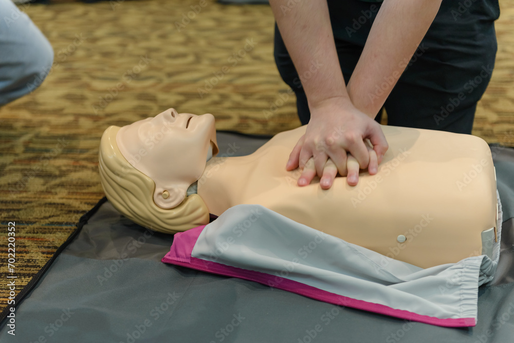 CPR First Aid Training with CPR dummy in the class. Demonstrating chest ...