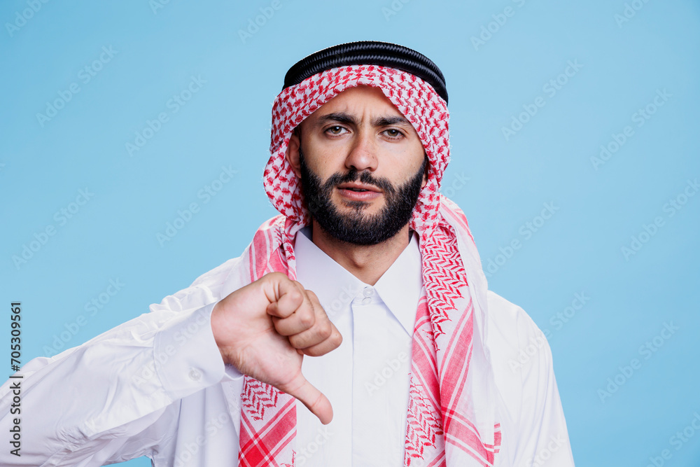 Muslim man dressed in traditional headdress showing thumb down negative ...