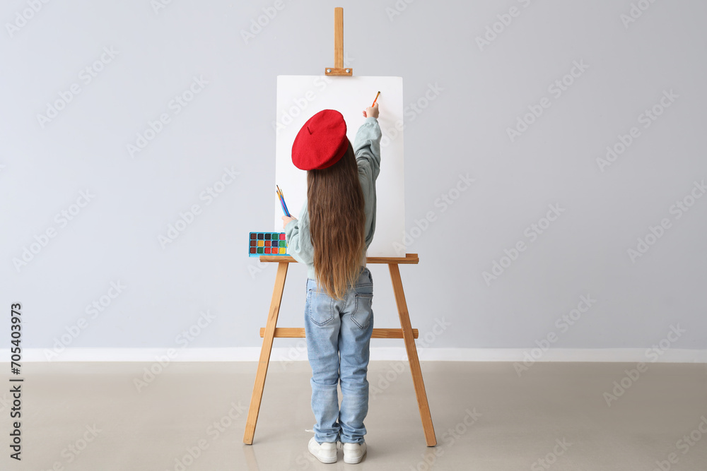 Stock-Foto „Cute little artist drawing on easel near light wall ...