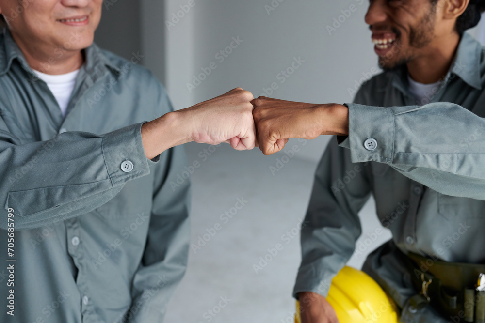 Positive construction engineers making fist bump after finishing day at ...