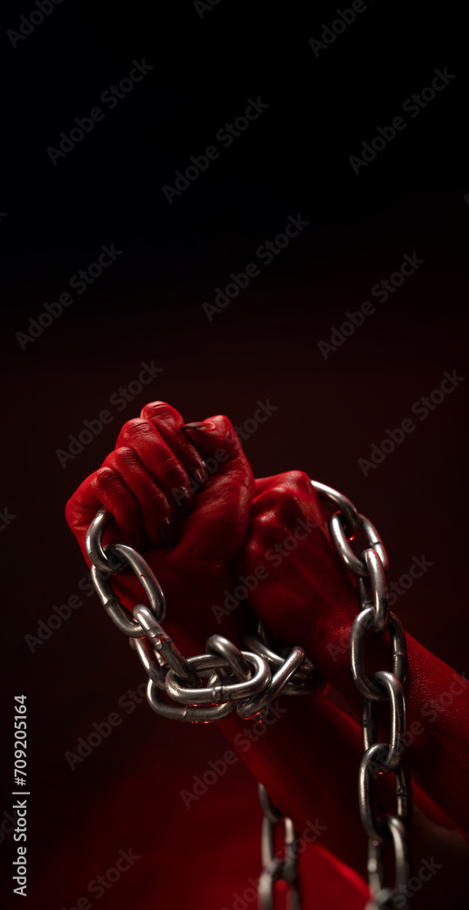 bloodied hands clenched into fists in the shackles of a metal chain ...