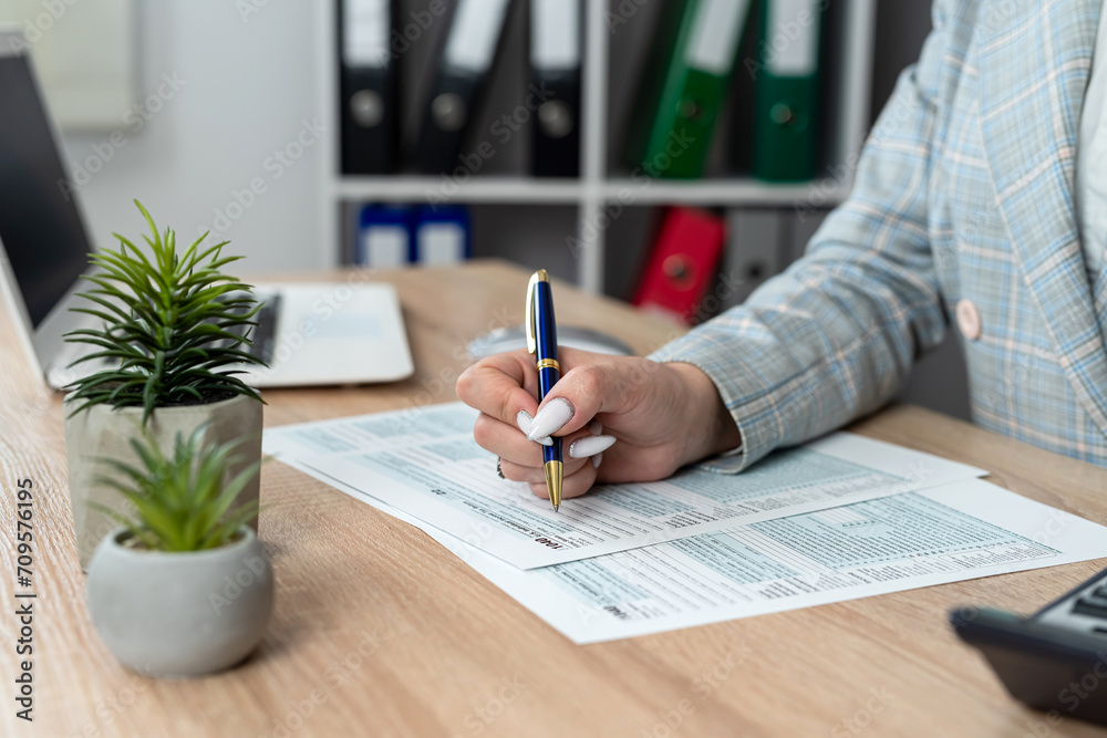 Business woman filling individual income tax return form, tax documents ...