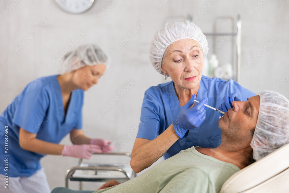 Team of cosmetologists provide anti-aging injection services to male ...