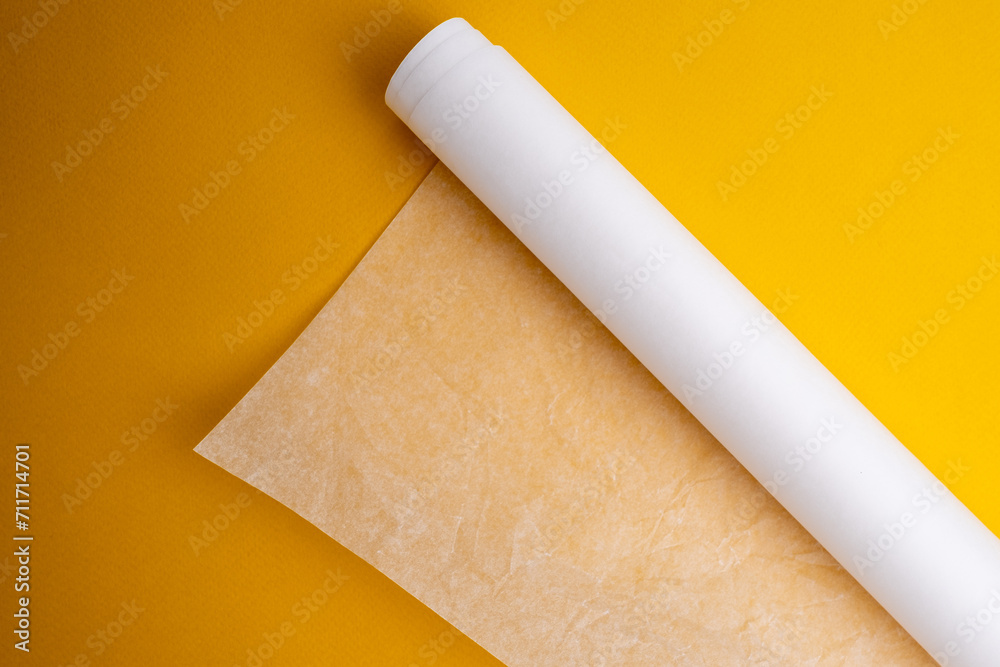 Plastic wrap, aluminum foil and a roll of parchment paper on a yellow ...