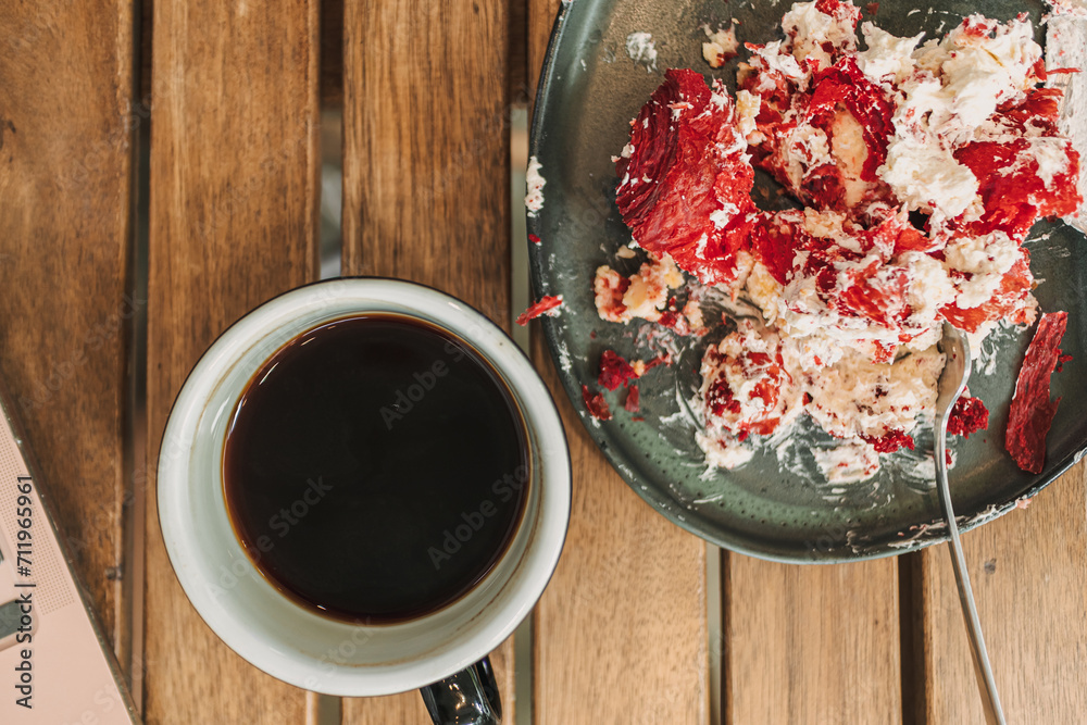 Messed up strawberry cake and cream on the dish with a cup of coffee ...