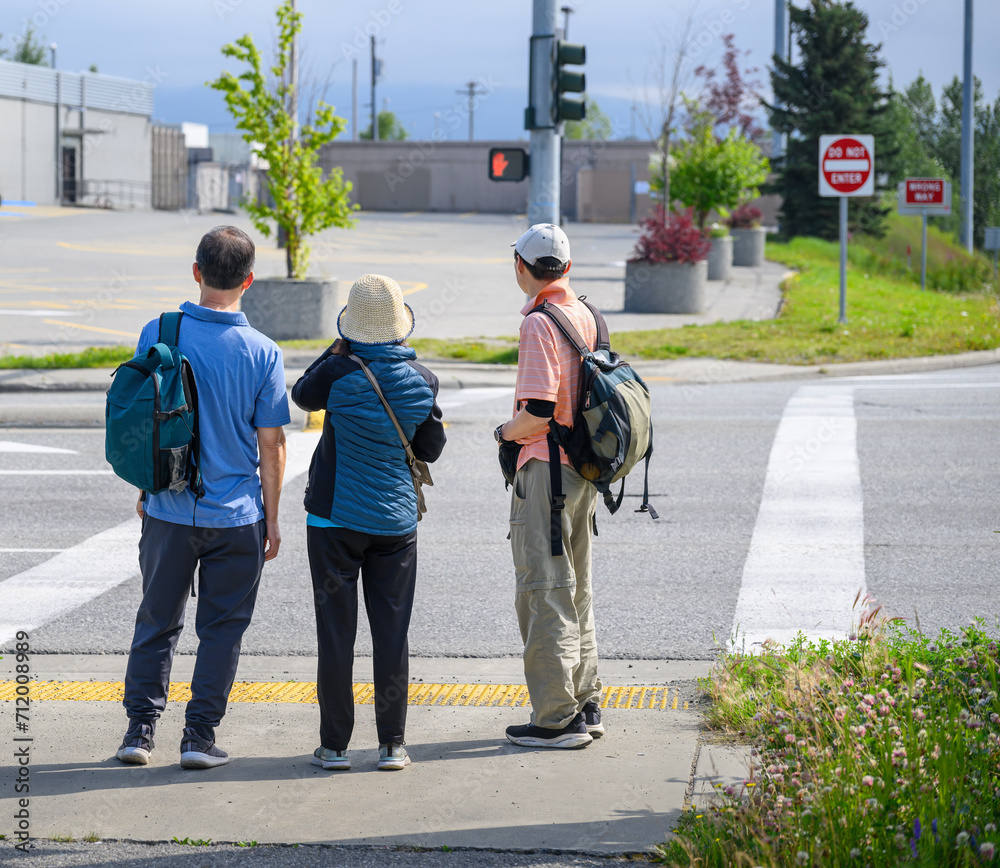 Three people waiting at the intersection. Red hand pedestrian stop sign ...
