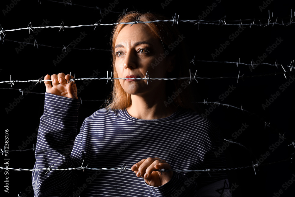 Mature Jewish woman behind barbed wire on black background ...