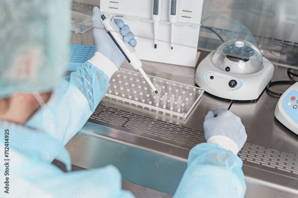 Back view of scientist is using micropipette for biochemical test ...