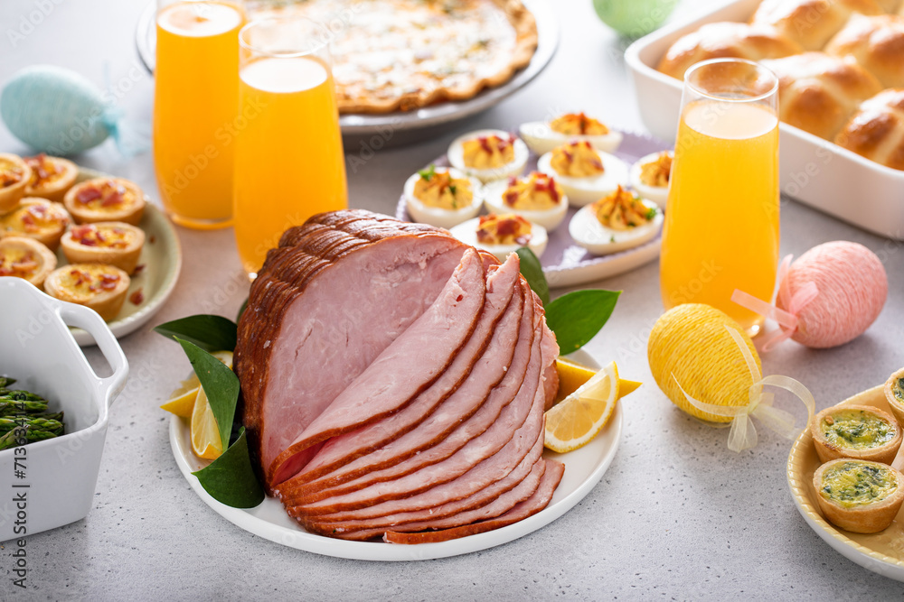 Easter brunch on large table with spiral sliced ham, quiche, deviled ...