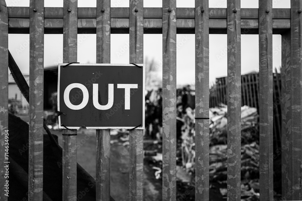 Out only sign seen on an industrial gate. Landfill material can be seen ...