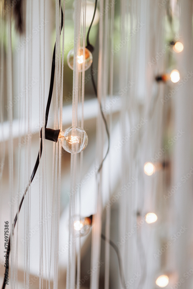 Hanging bulbs illuminate a serene space, casting a warm glow. The black ...