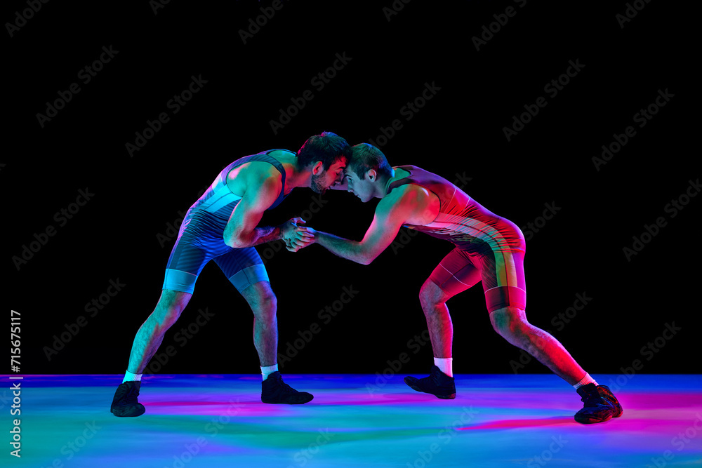 Young athlete man, wrestlers in blue and red uniform hand wrestling in ...