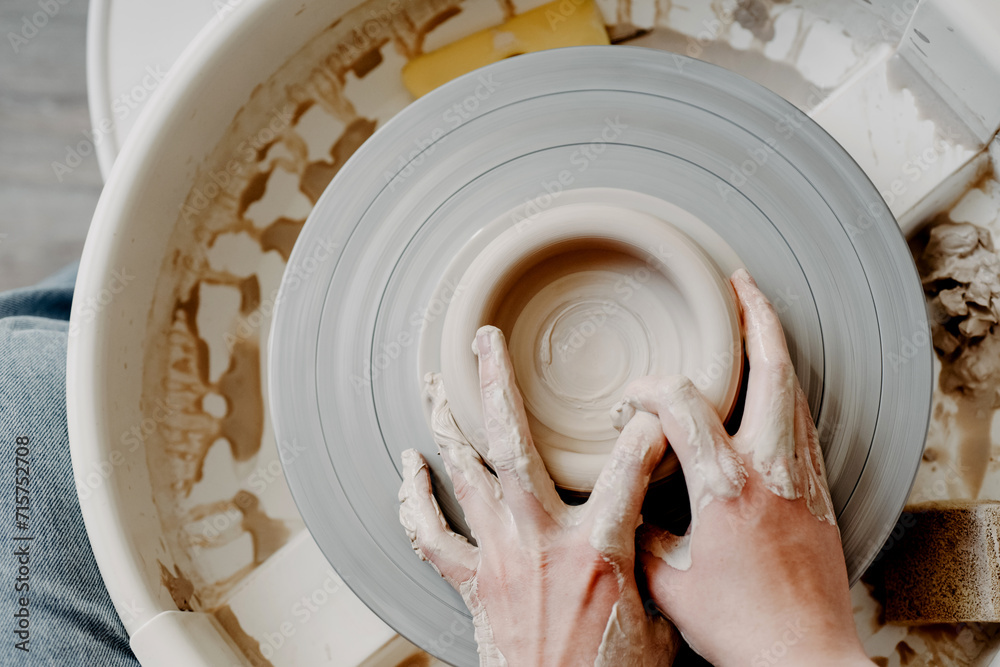 Female hands of a potter forming a clay product on a potter's wheel ...