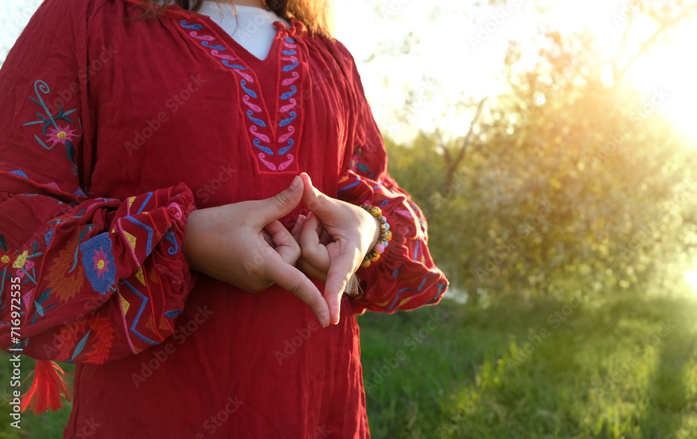 Woman on a red dress outdoor, doing meditation yoga mudra of hands ...