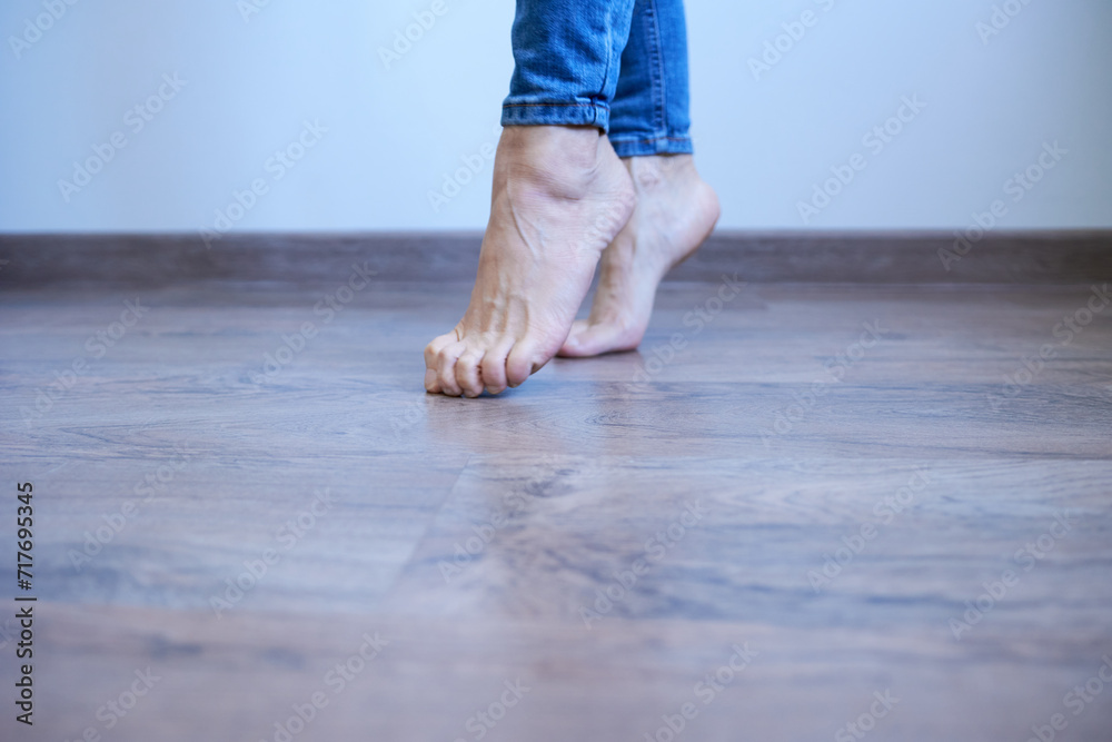 Barefoot girl in jeans standing on tiptoes indoors modern house. Women ...