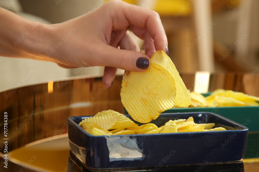 Young sad woman having unhealthy snack, eating potato chips in the ...