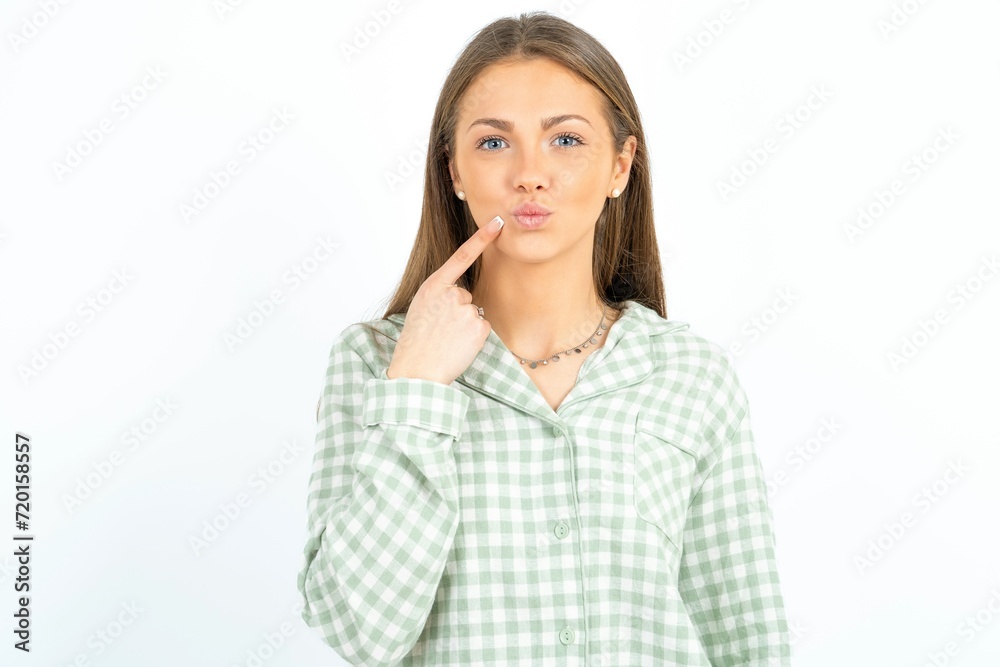 Charming young beautiful woman wearing green plaid pyjama, pointing on ...