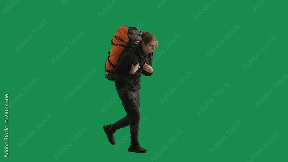 Side view of a tired hiker in full length walking with a heavy backpack ...