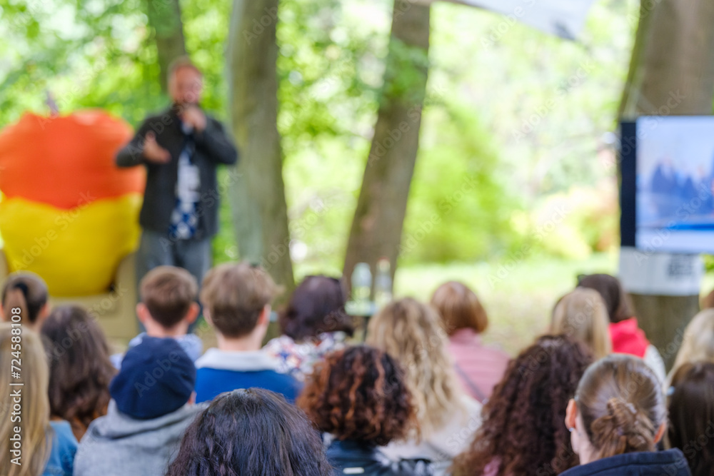 Blurred outdoor audience engaging in a workshop with a speaker in ...