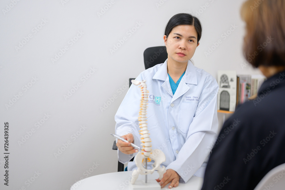 Aging and back pain concept: Female orthopedic doctor shows her senior ...