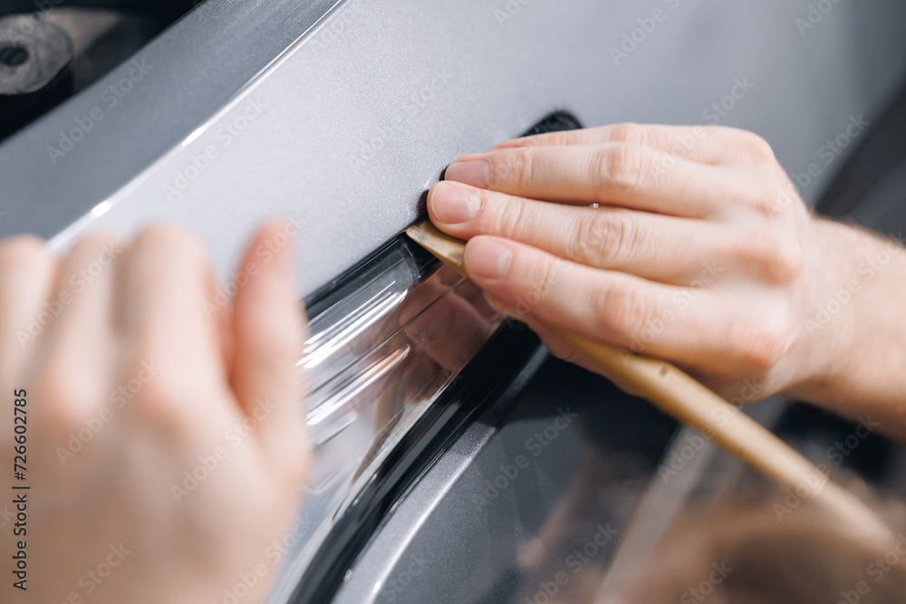 Foto de Stock Master tucks edge of protective vinyl film behind of car ...