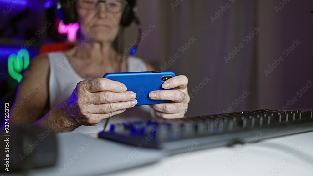 Cool grey-haired senior woman streamer rocks the gaming world, playing ...