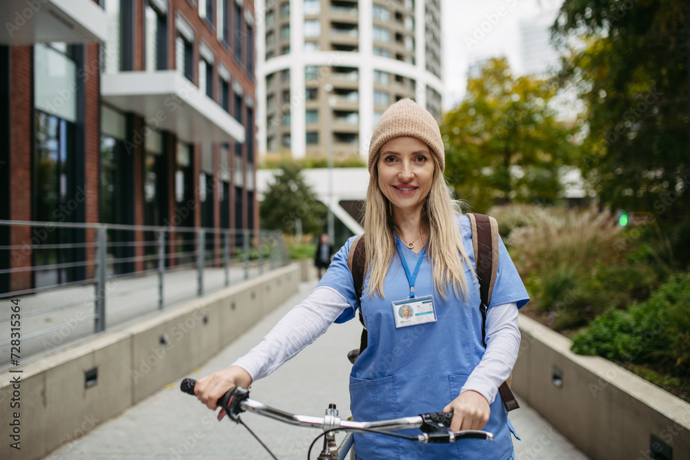 Beautiful nurse commuting through the city by bike. Doctor city ...