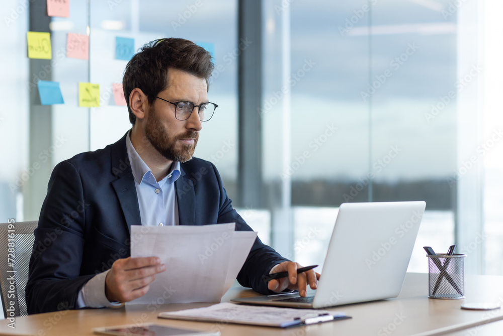 Serious and focused financier accountant on paper work inside office ...