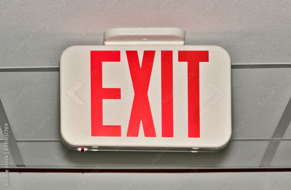 Exit sign isolated on a ceiling indoors in a building. Commonly posted ...