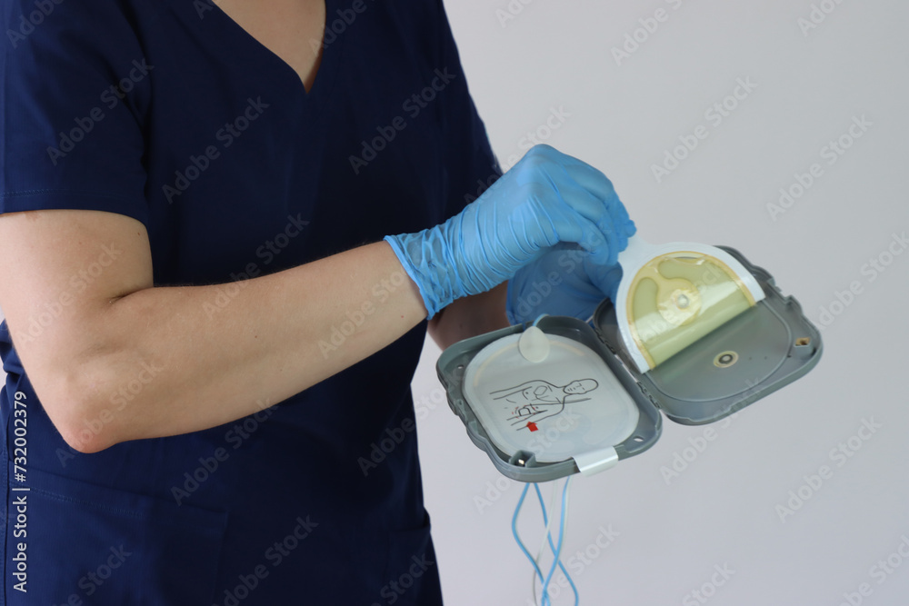 Health care professional wearing gloves taking off the defibrillator ...