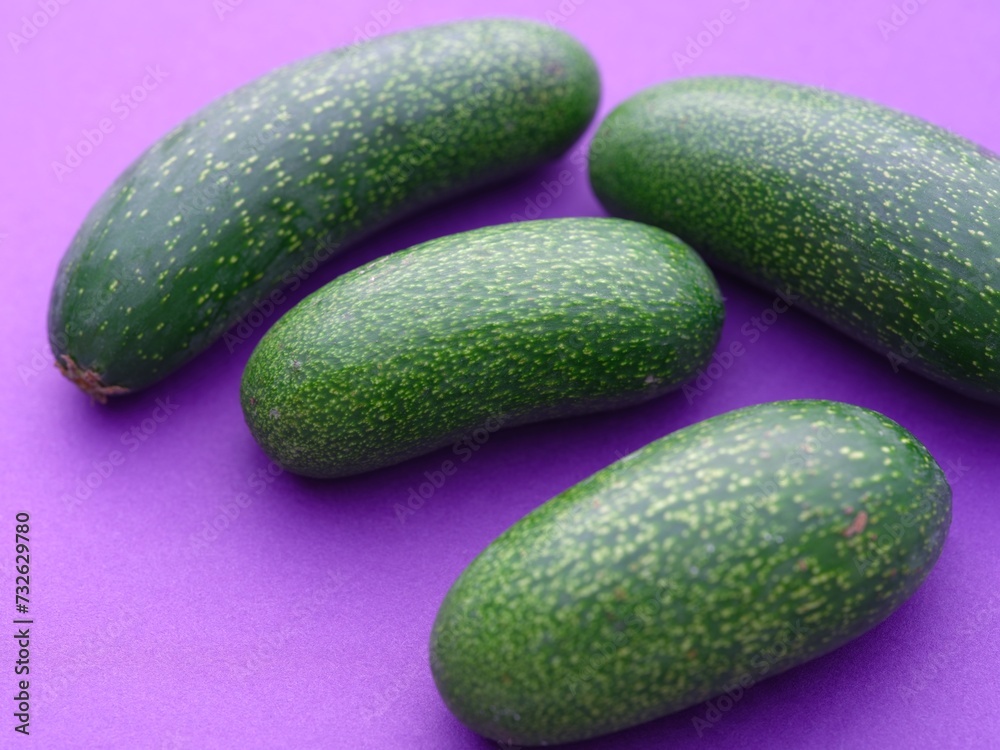 Four cocktail avocados or mini avocados on a purple background ...