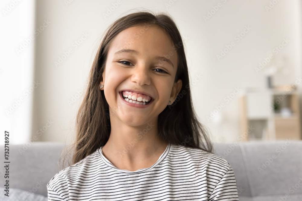 Happy cute pre teen kid girl looking at camera with toothy smile ...