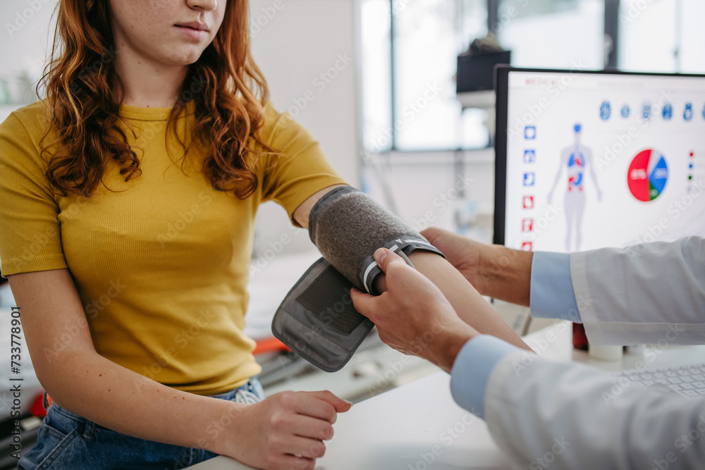 Doctor examining teenage girl, measuring blood pressure, using clinical ...