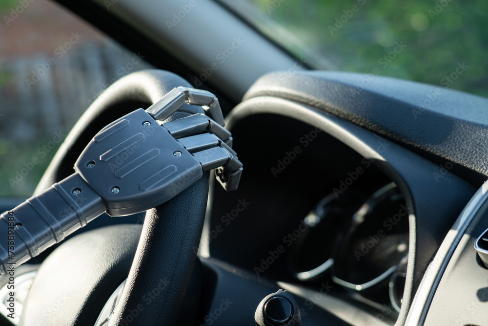Robot arm on a steering wheel. Artificial intelligence drives a car ...