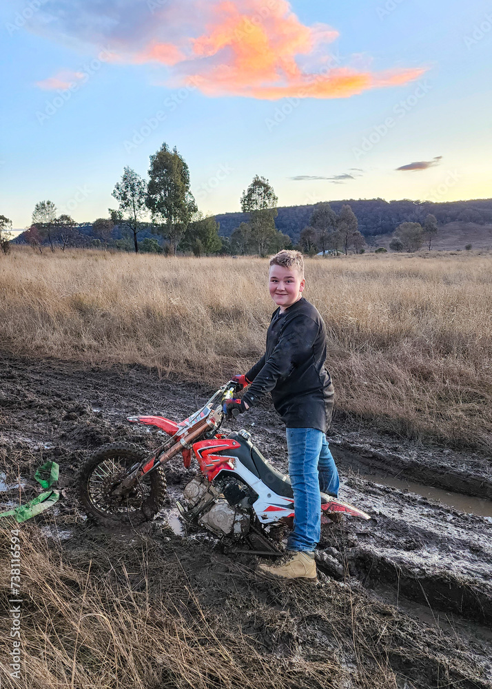 Teen boy on farm with motorbike stuck in the mud Stock Photo | Adobe Stock