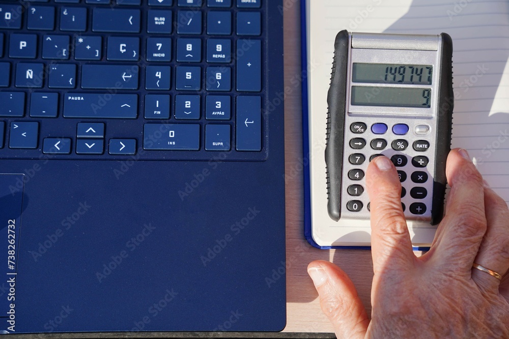 an unrecognizable old woman working with laptop and income tax return ...