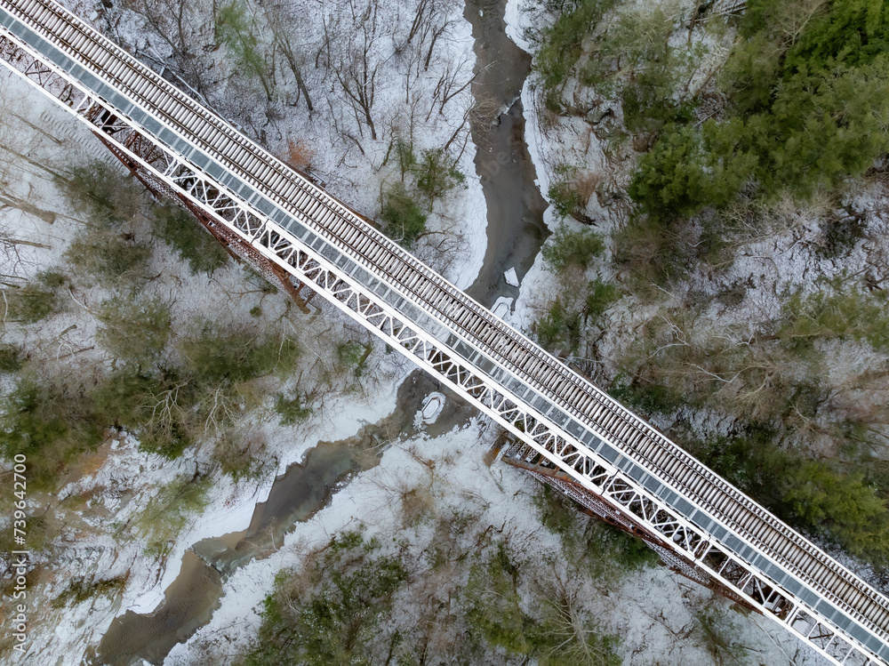 Winter aerial photos of a rusty old iron railway bridge over a forest ...