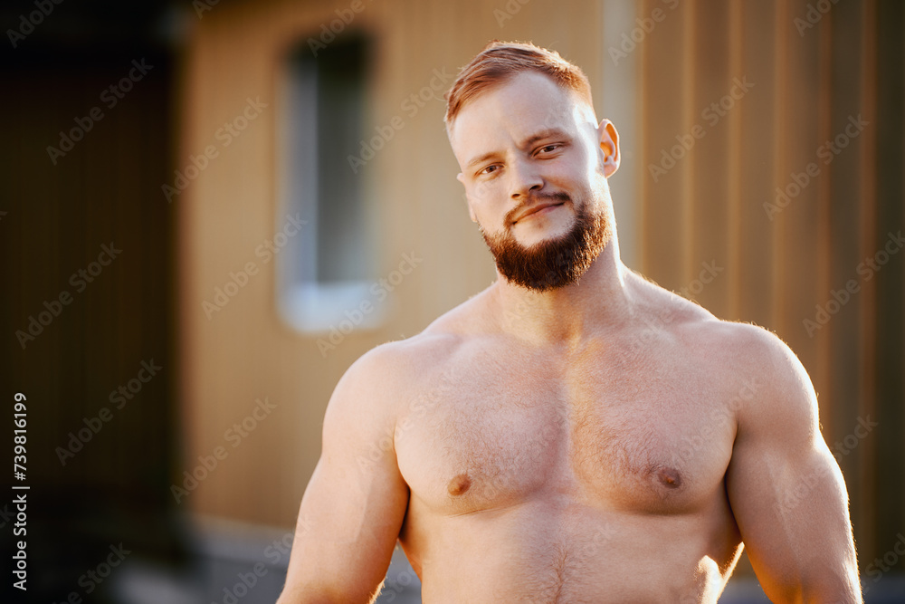 Smug shirtless muscular man outdoors near wooden farmhouse in ...