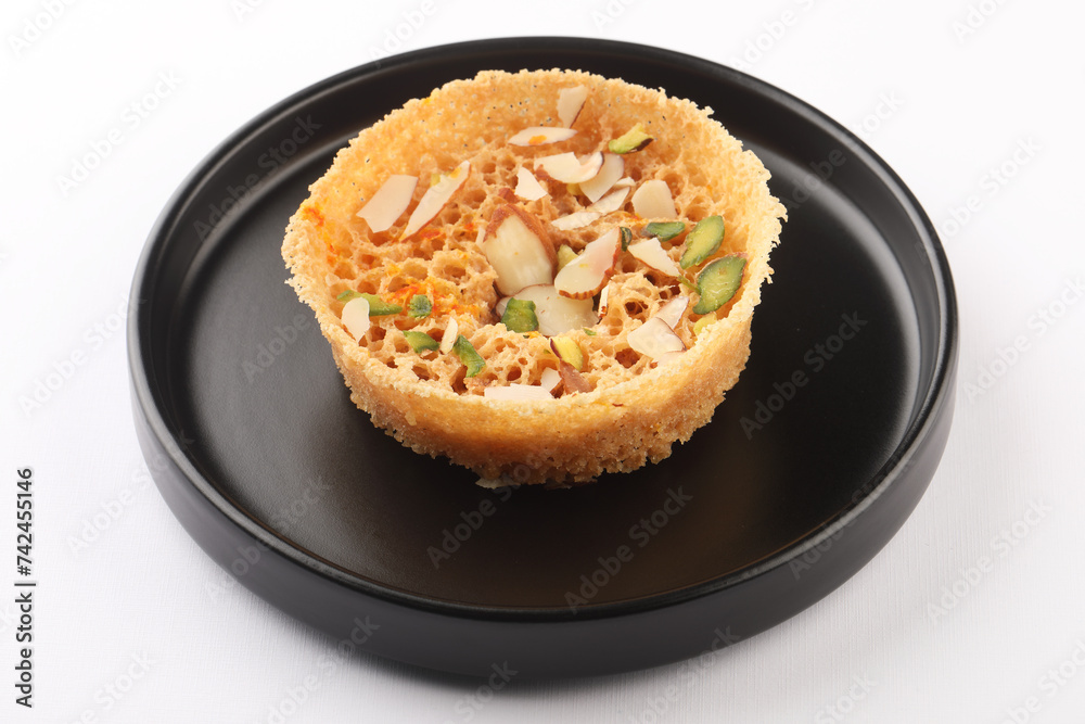 Ghewar made with ghee and flour and soaked in sugar syrup, traditional ...