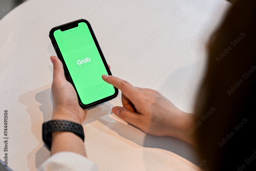 Chiang Mai, Thailand - Feb 24, 2024: A woman uses the Grab application ...