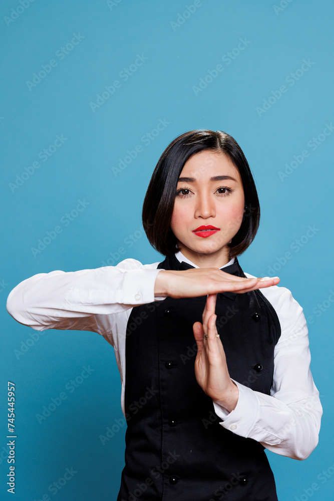 Serious asian waitress in uniform showing timeout sign with hands ...