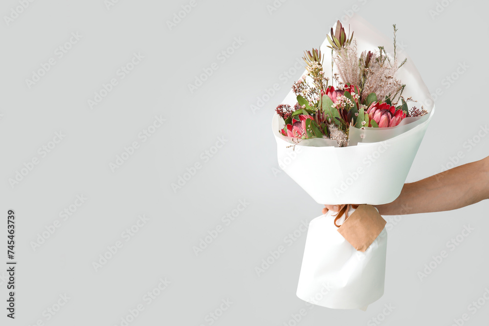Male hand with bouquet of beautiful flowers on grey background Stock ...
