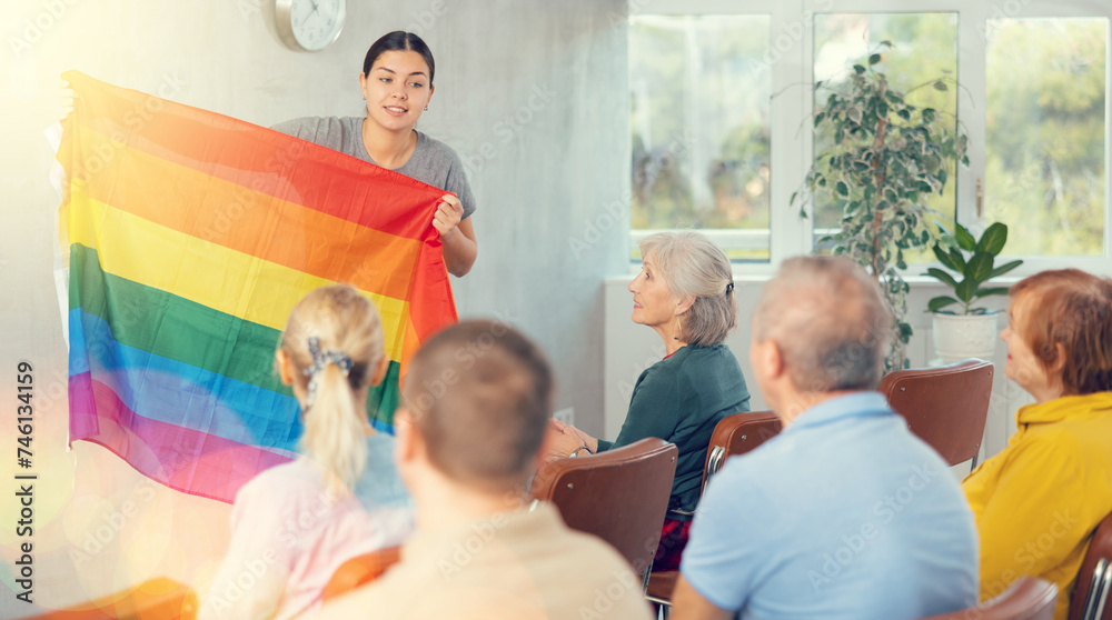 Emotional young female tutor showing rainbow flag while talking about ...