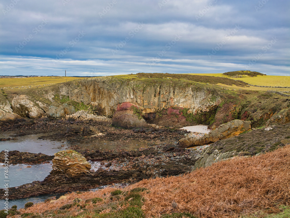 Colourful coastal cliffs on the Wales Coast Path. The rocks are of the ...