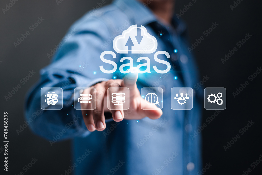 SaaS, software as a service concept. Businessman touching cloud SaaS icon on virtual screen ...