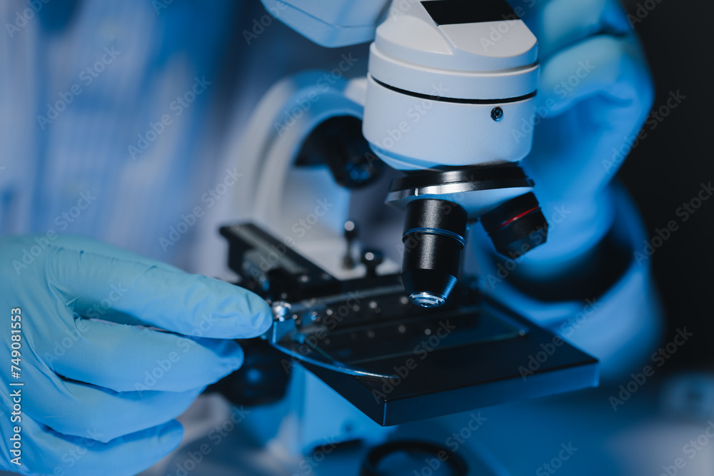 A scientist is studying samples using a microscope to study and develop the field of ...