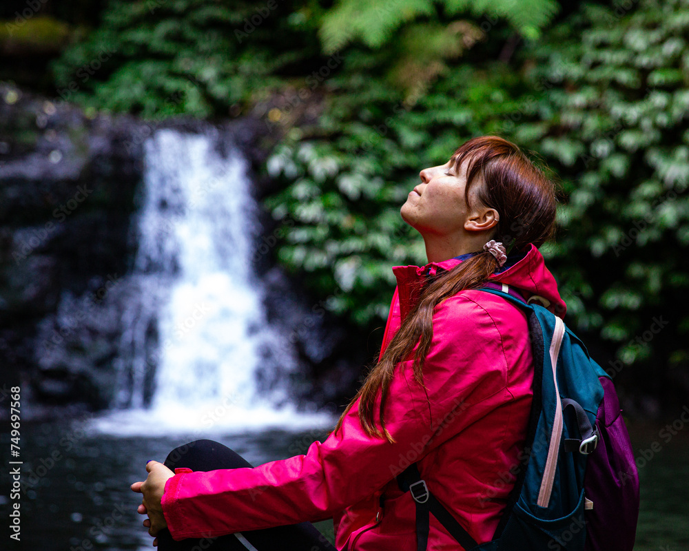 relaxed hiker girl sitting in front of a tropical waterfall; toolona ...
