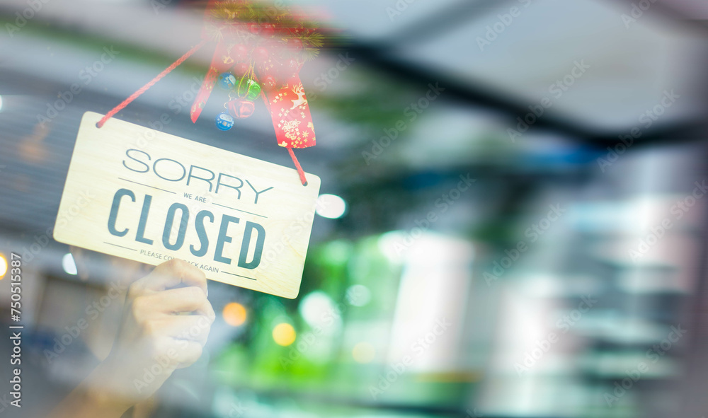 The waitress man turning Closed sign board on glass door in modern cafe ...