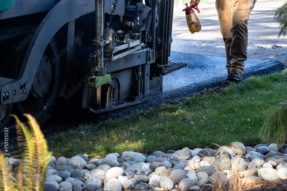 Road repaving project, man walking next to an asphalt paving machine ...