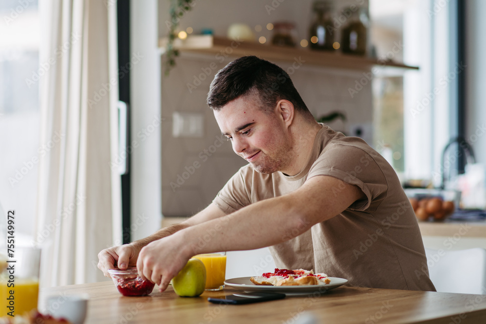 Young man with Down syndrome preparing breakfast on his own. Morning ...